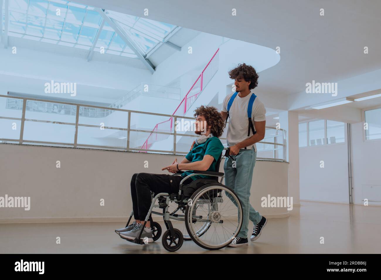 African American student pushing his friend's wheelchair through a ...