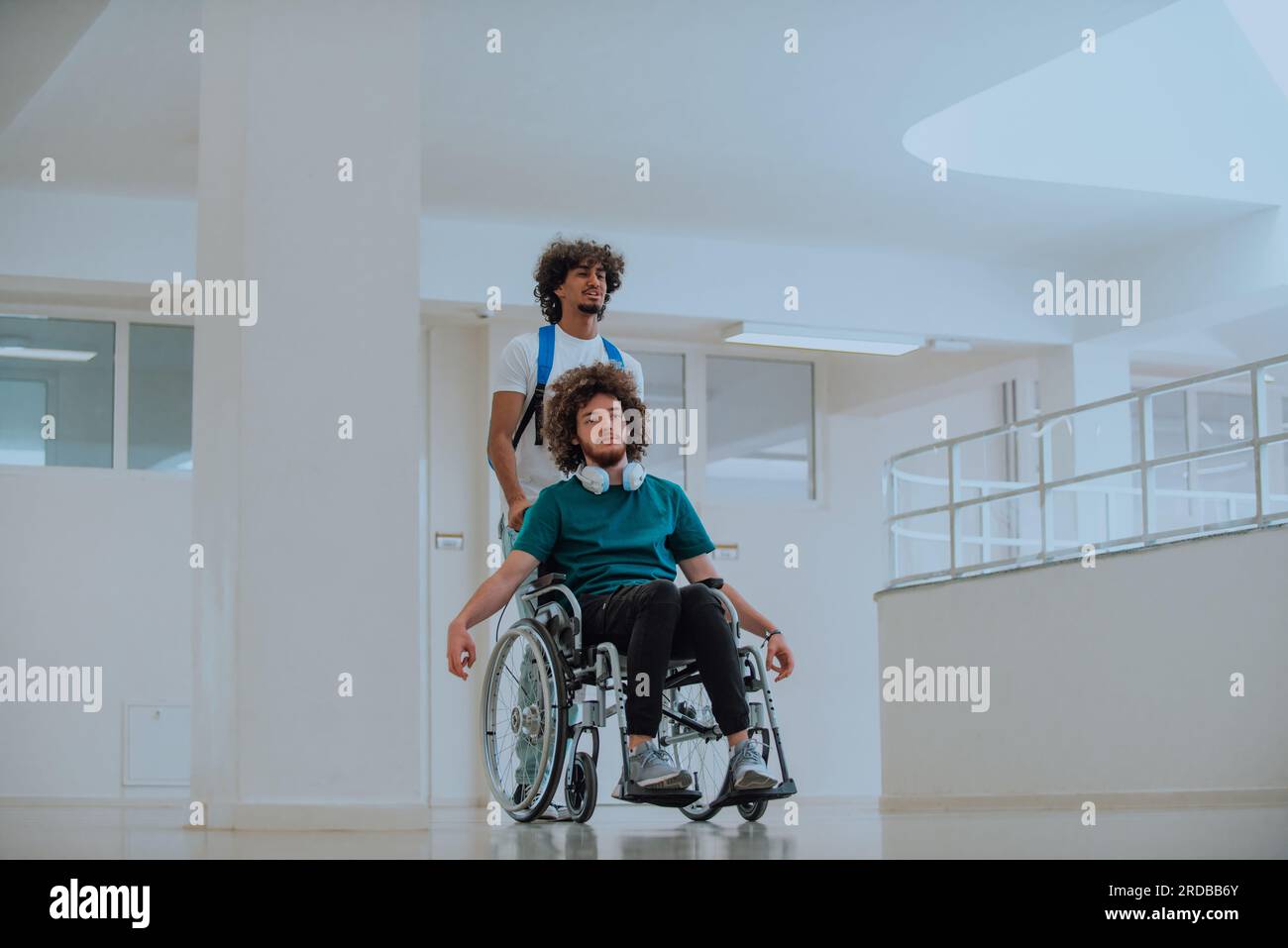 African American student pushing his friend's wheelchair through a ...