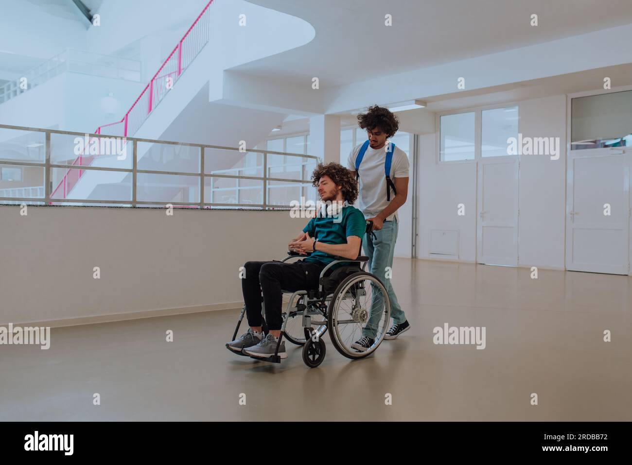 African American student pushing his friend's wheelchair through a ...