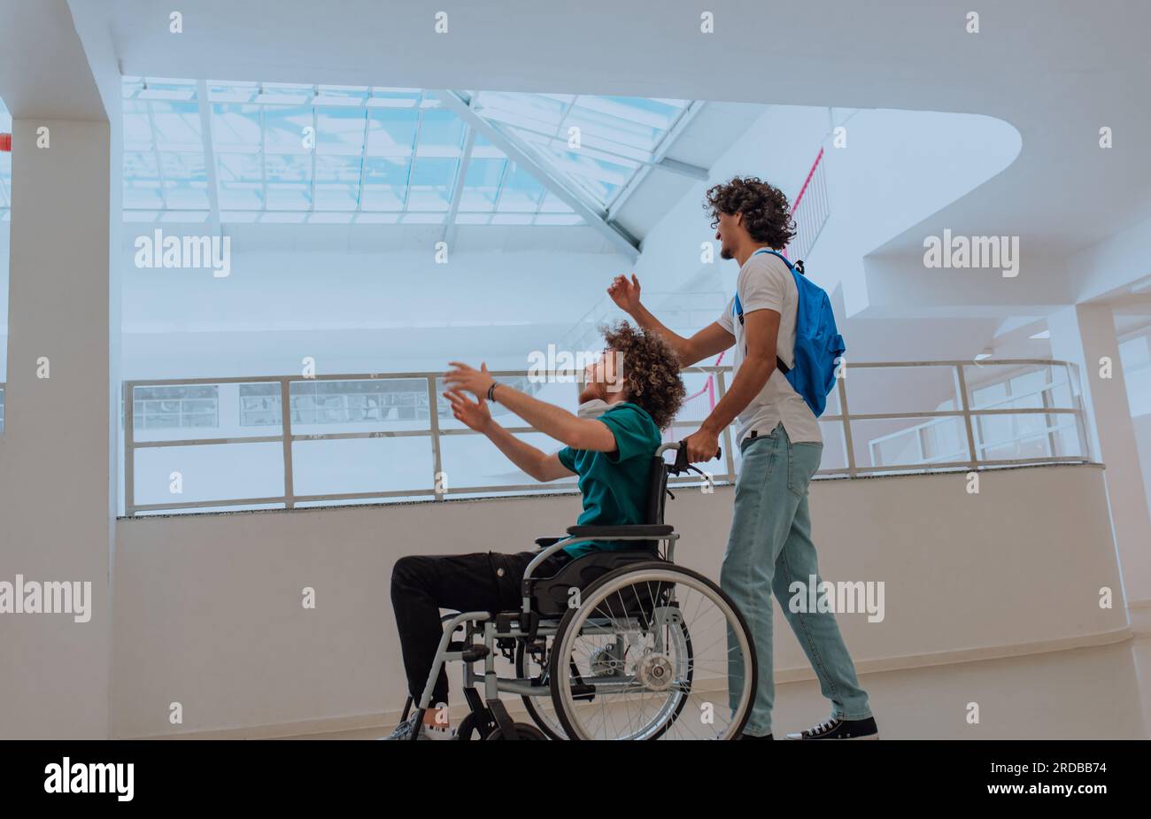 African American student pushing his friend's wheelchair through a ...