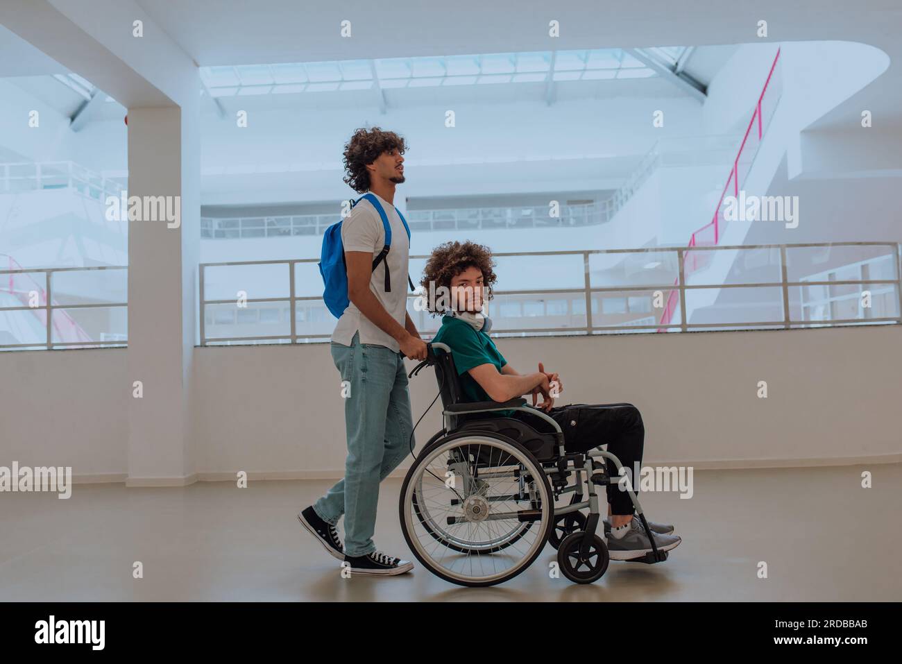 African American student pushing his friend's wheelchair through a ...