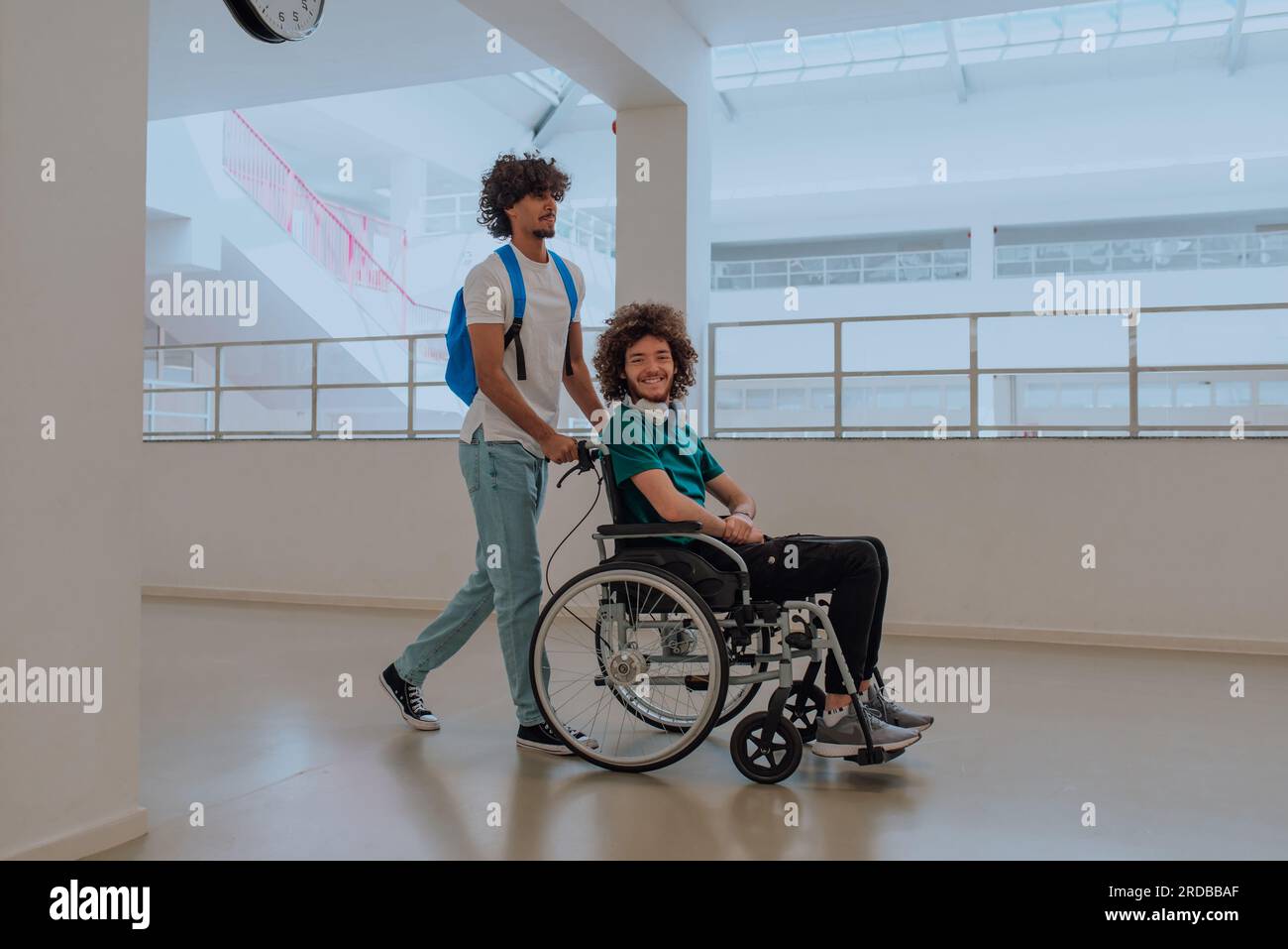 African American student pushing his friend's wheelchair through a ...