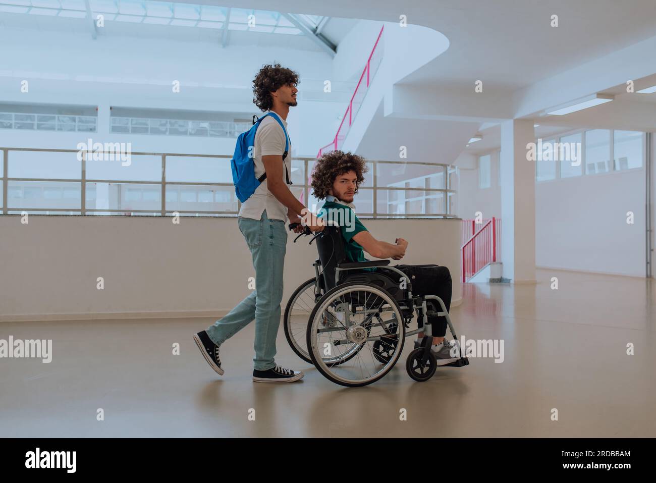 African American student pushing his friend's wheelchair through a ...