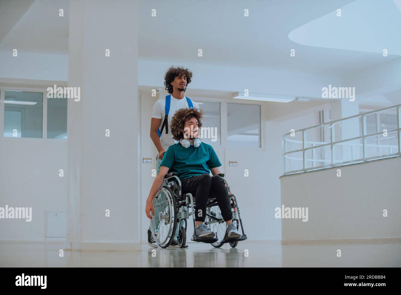 African American student pushing his friend's wheelchair through a ...