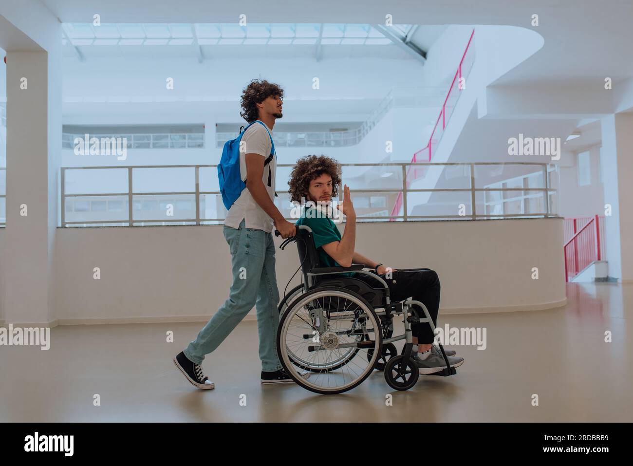 African American student pushing his friend's wheelchair through a ...