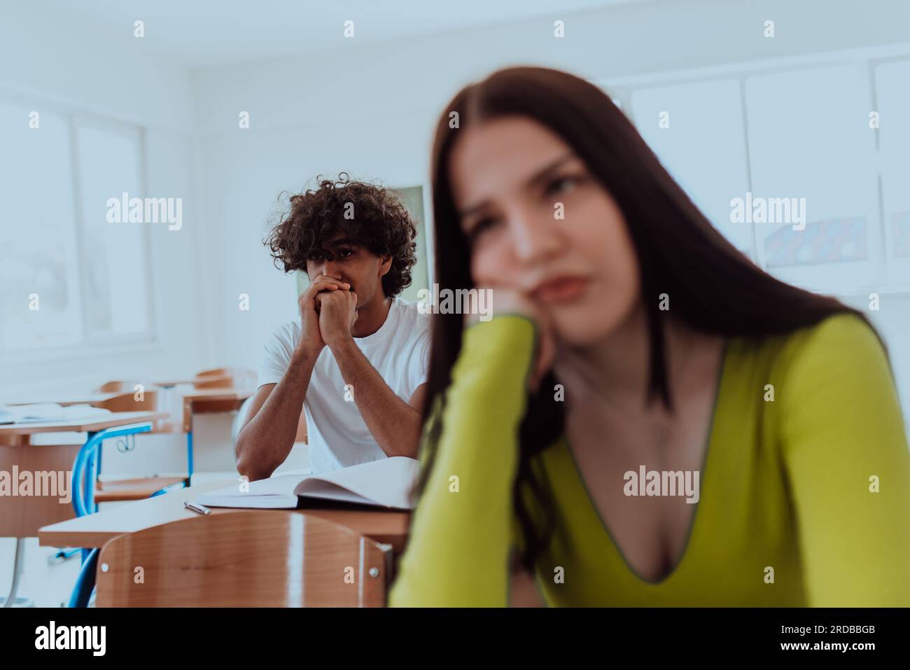 A weary-looking student sitting in front of a group of diverse students ...