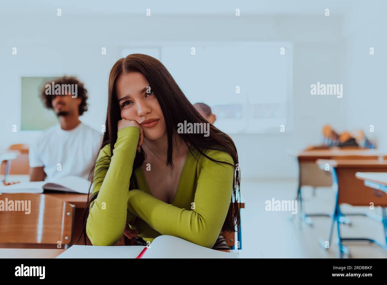 A weary-looking student sitting in front of a group of diverse students ...