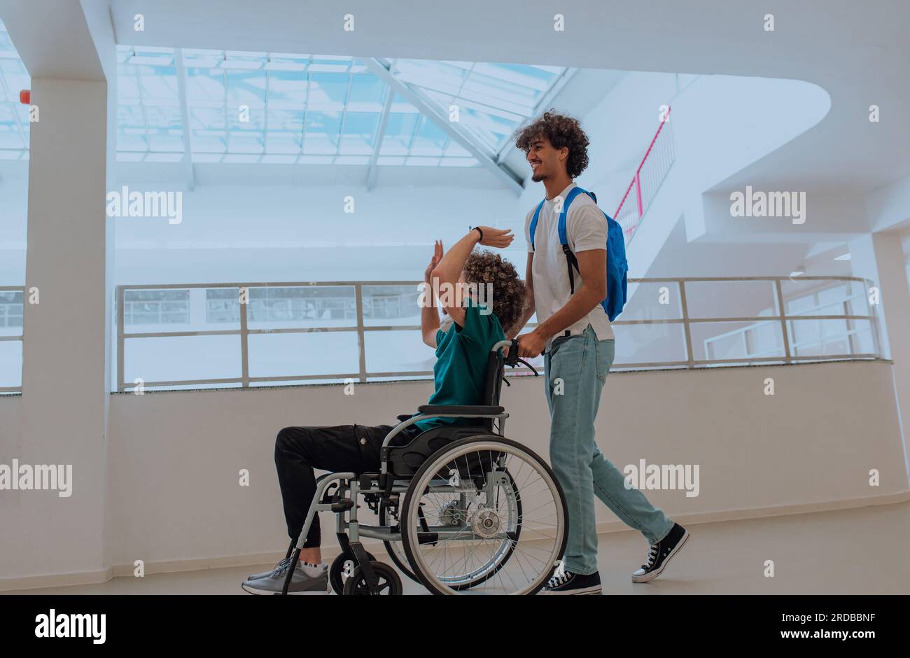 African American student pushing his friend's wheelchair through a ...