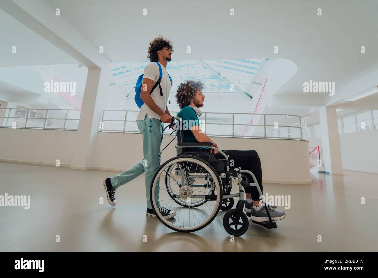African American student pushing his friend's wheelchair through a ...