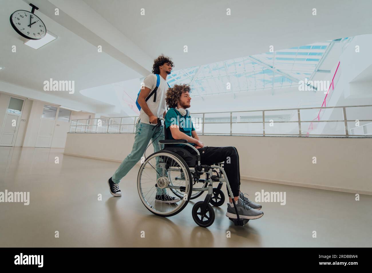 African American student pushing his friend's wheelchair through a ...