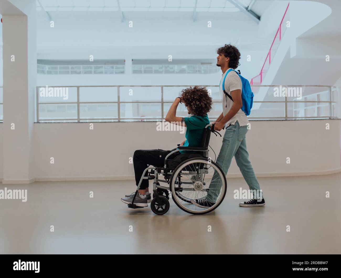 African American student pushing his friend's wheelchair through a ...