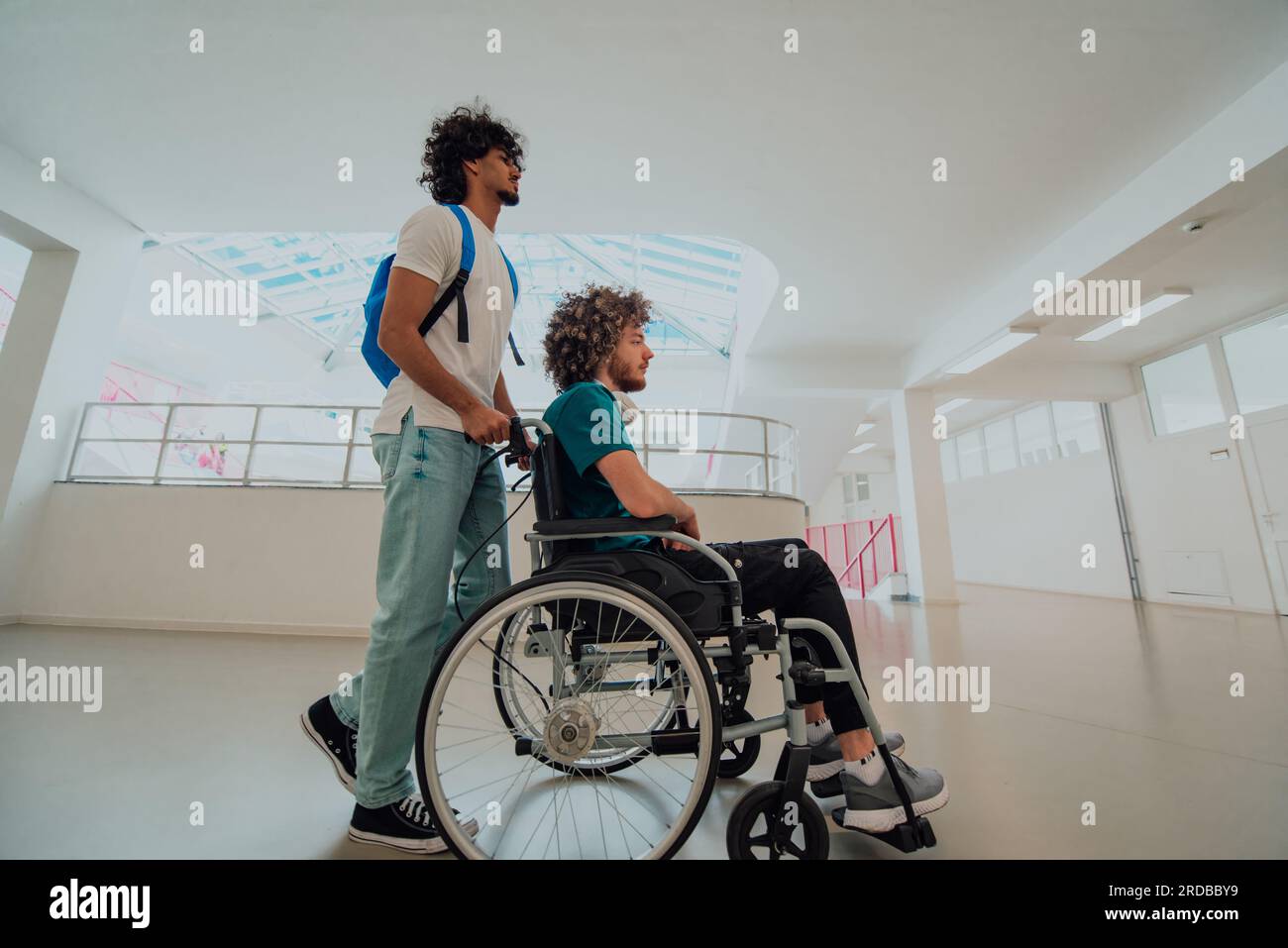 African American student pushing his friend's wheelchair through a ...