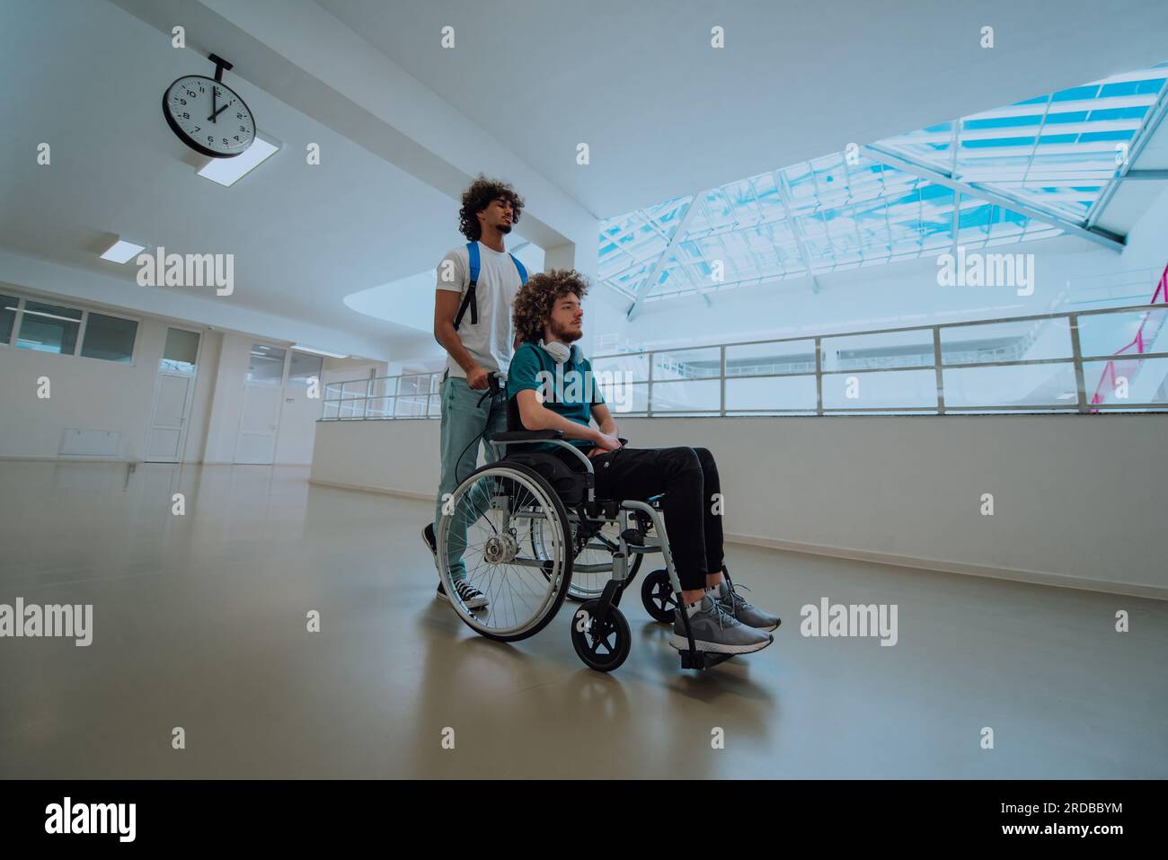 African American student pushing his friend's wheelchair through a ...