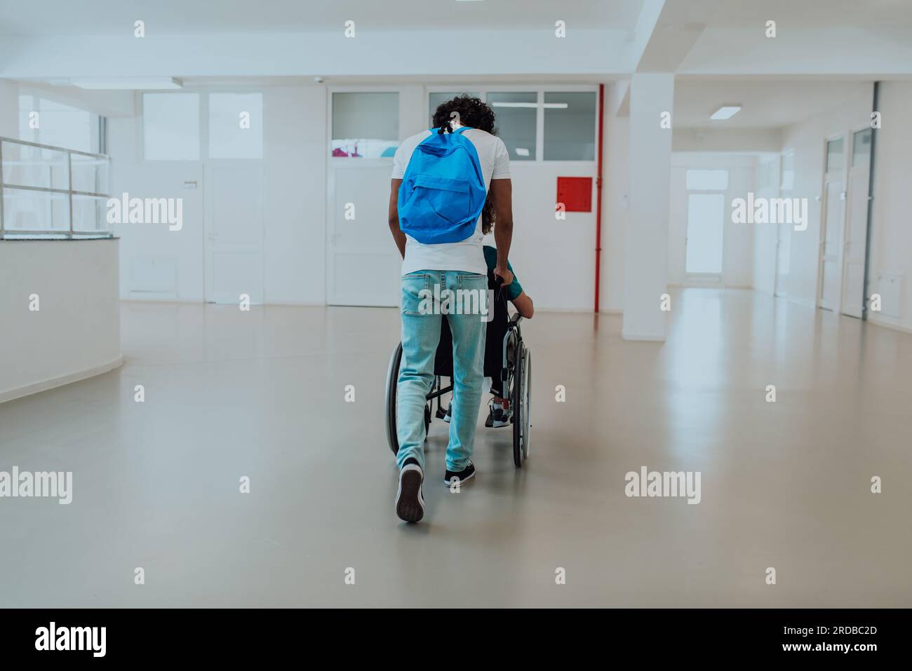 African American student pushing his friend's wheelchair through a ...