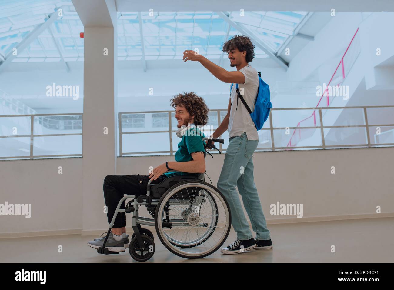 African American student pushing his friend's wheelchair through a ...