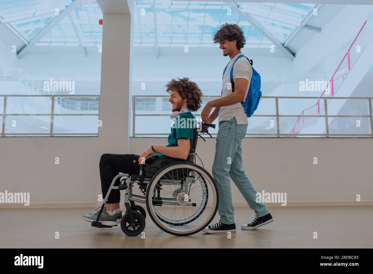 African American student pushing his friend's wheelchair through a ...