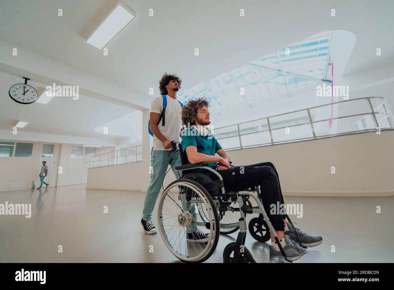African American student pushing his friend's wheelchair through a ...