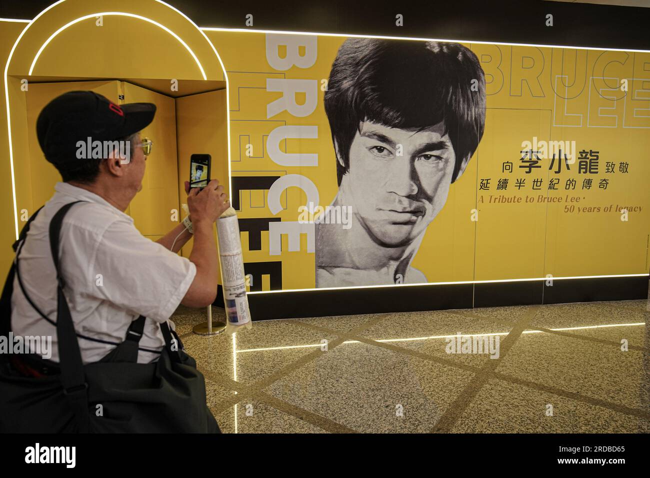 A man takes photos in front of a poster of Bruce Lee in the exhibition ...