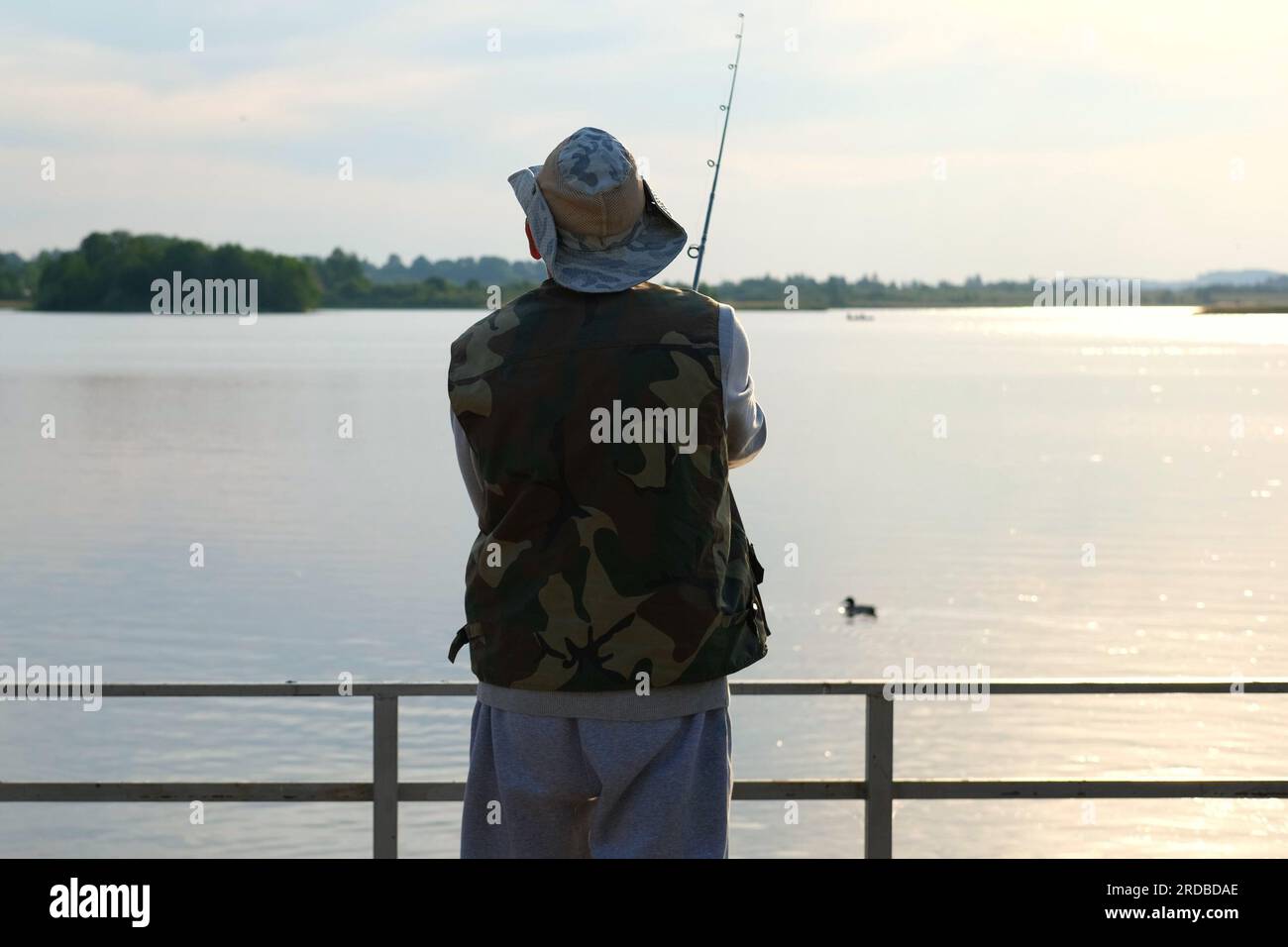 Old man fishing. Senior gray haired fisherman throws a spinning from ...