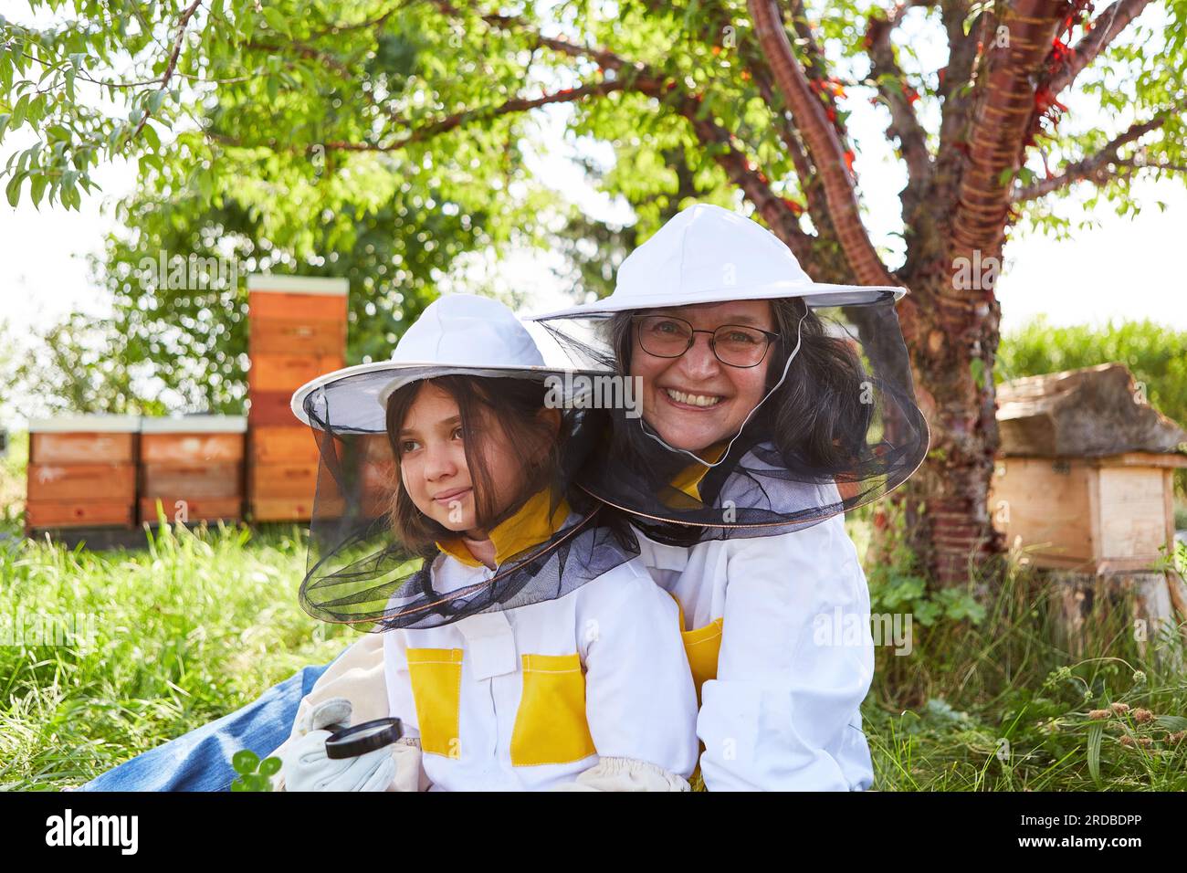 Portrait of smiling senior female beekeeper with girl holding ...