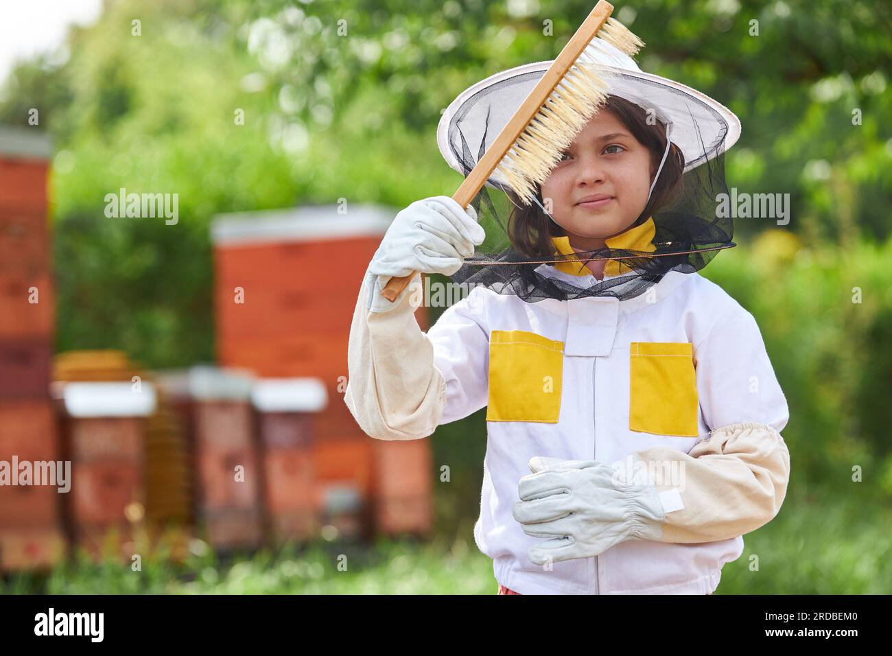 Girl analyzing hive brush wearing protective suit at apiary garden ...