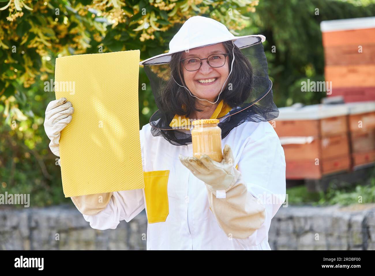 Female beekeeper offering bee honey and beeswax sheets in front of ...