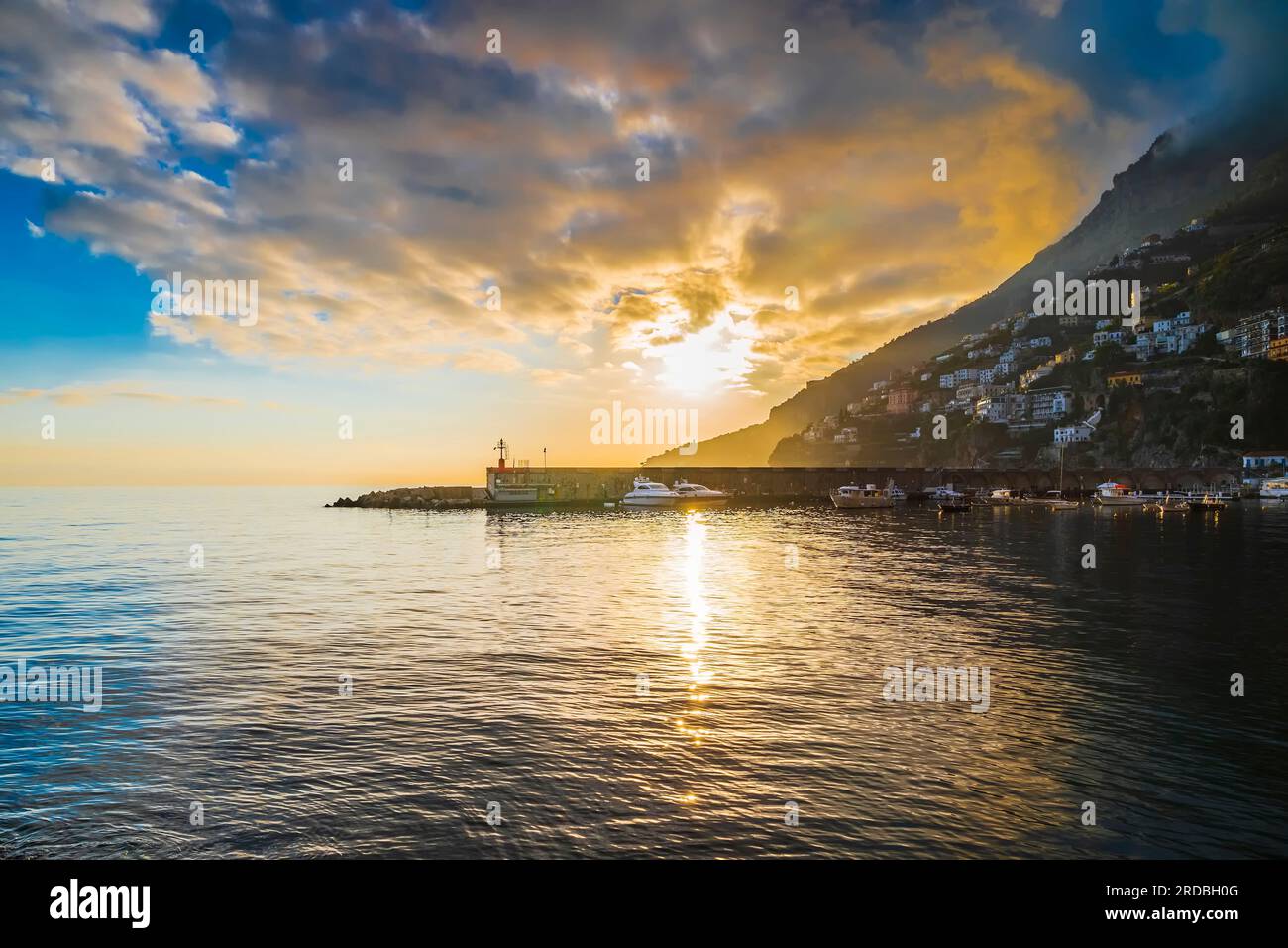 Crepuscular sun rays streaming through the clouds over Amalfi shoreline ...