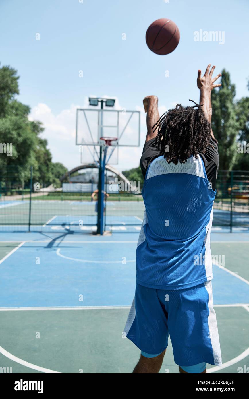 Concentrated young man, athlete in blue uniform playing basketball ...