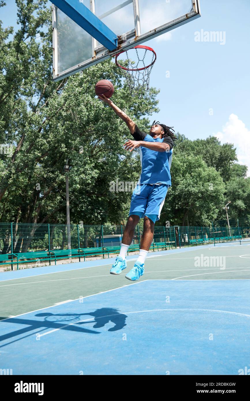 Concentrated young man, athlete in blue uniform playing basketball ...