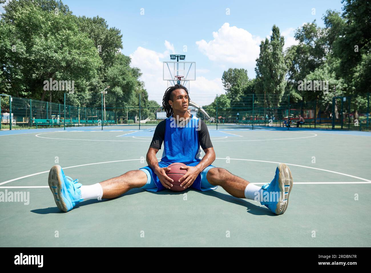 Young guy in blue uniform, basketball player sitting and resting after ...