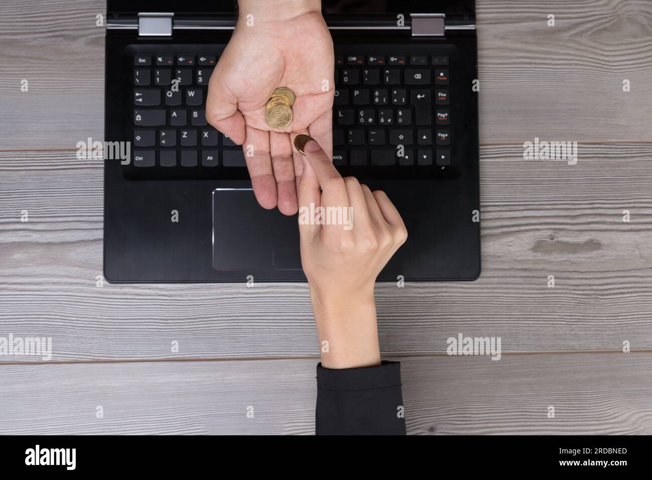 Overhead view of a hand paying and another receiving money through a ...