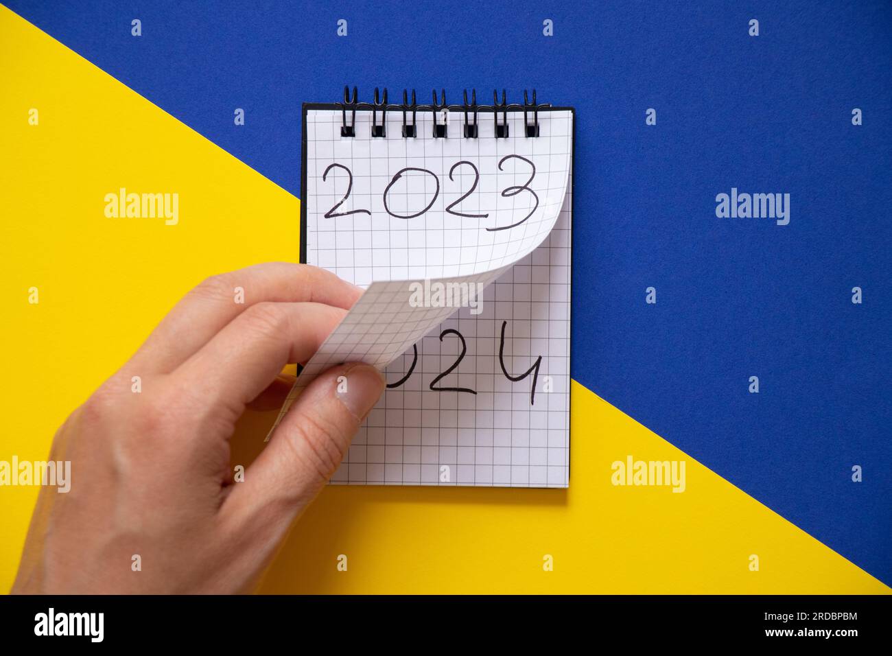Notepad with the text 2023 and 2024 and the hand turns the page of the ...