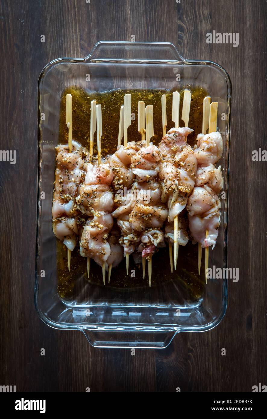 A glass dish of raw chicken marinading on bamboo skewers Stock Photo ...