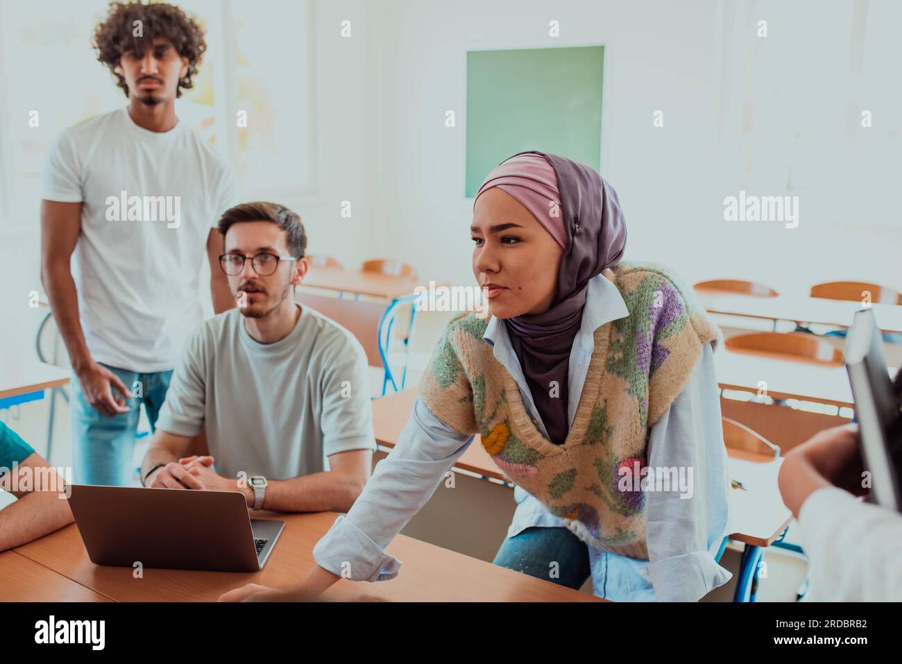 A diverse group of students gathers in a modern school classroom ...