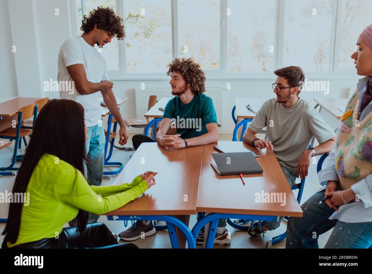 A diverse group of students gathers in a modern school classroom ...