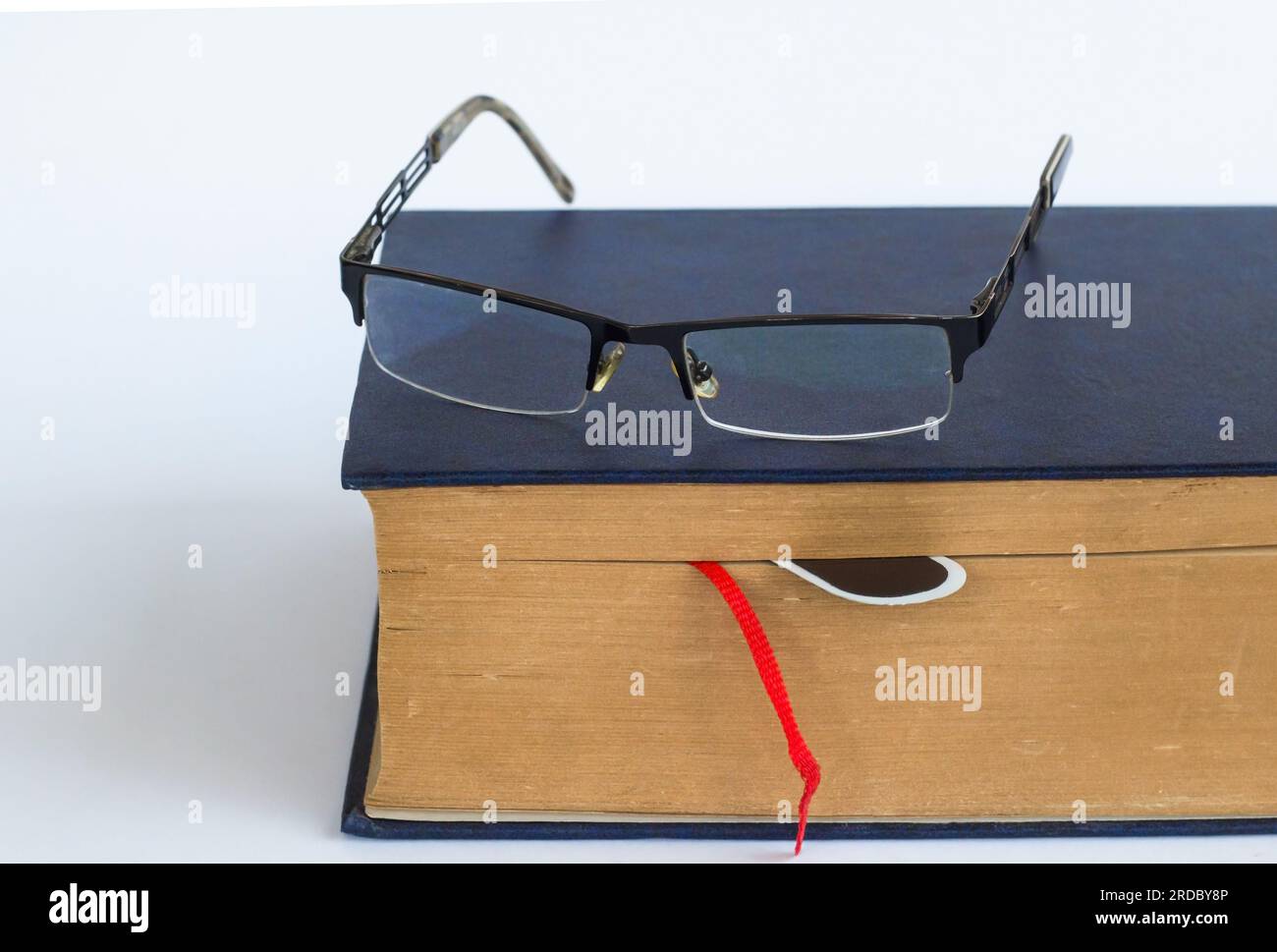 Hard cover old book on white surface with reading glasses and bookmark ...