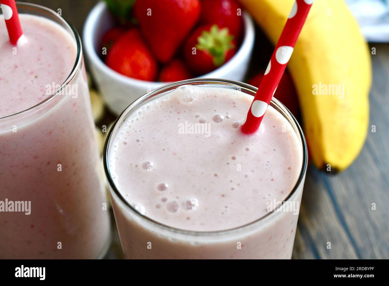 Strawberry banana smoothie in a clear glass on a rustic surface Stock ...