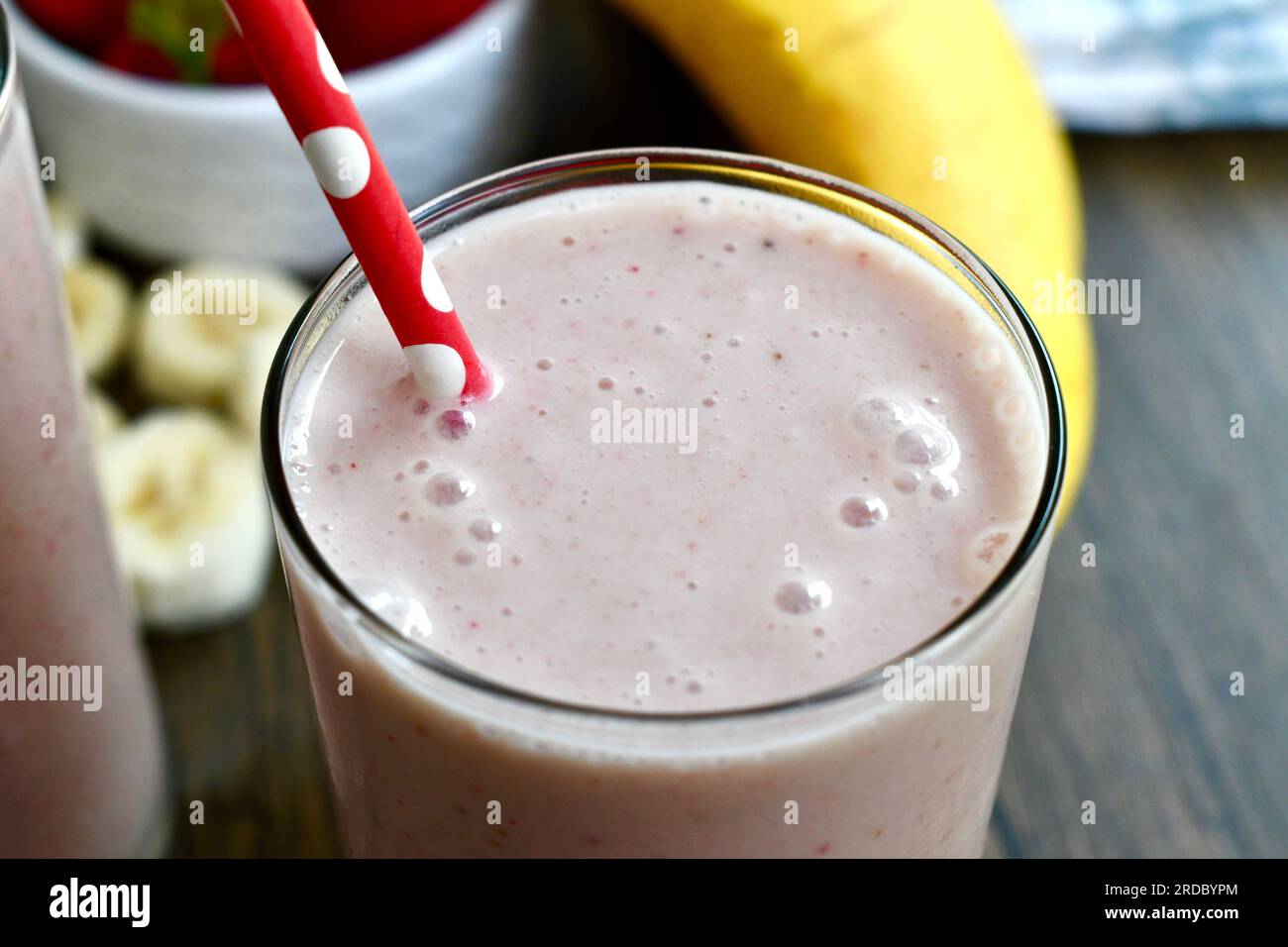 Strawberry banana smoothie in a clear glass on a rustic surface Stock ...