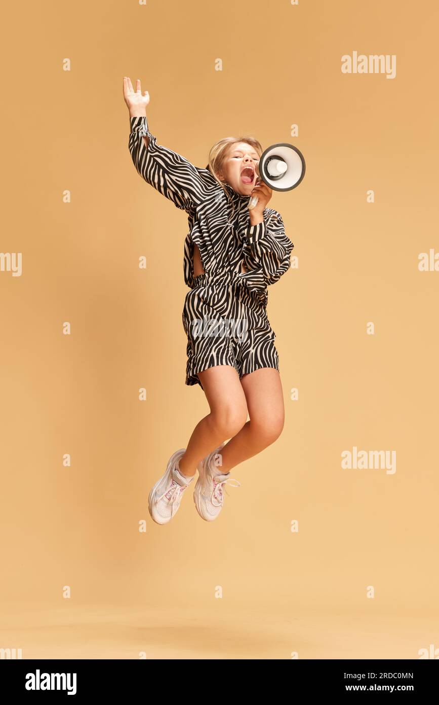 Full size beautiful child girl jumping with megaphone isolated over ...