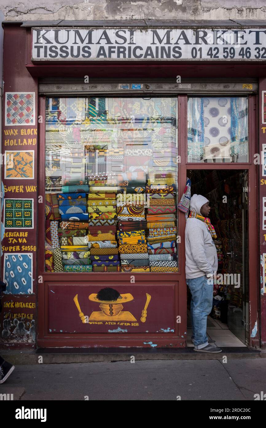 A man stands in the doorway of a shop selling African textiles in the ...