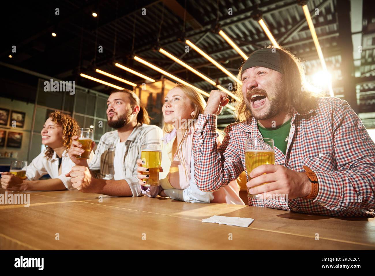 Excited sports fans, friends meeting at pub, drinking beer, watching ...