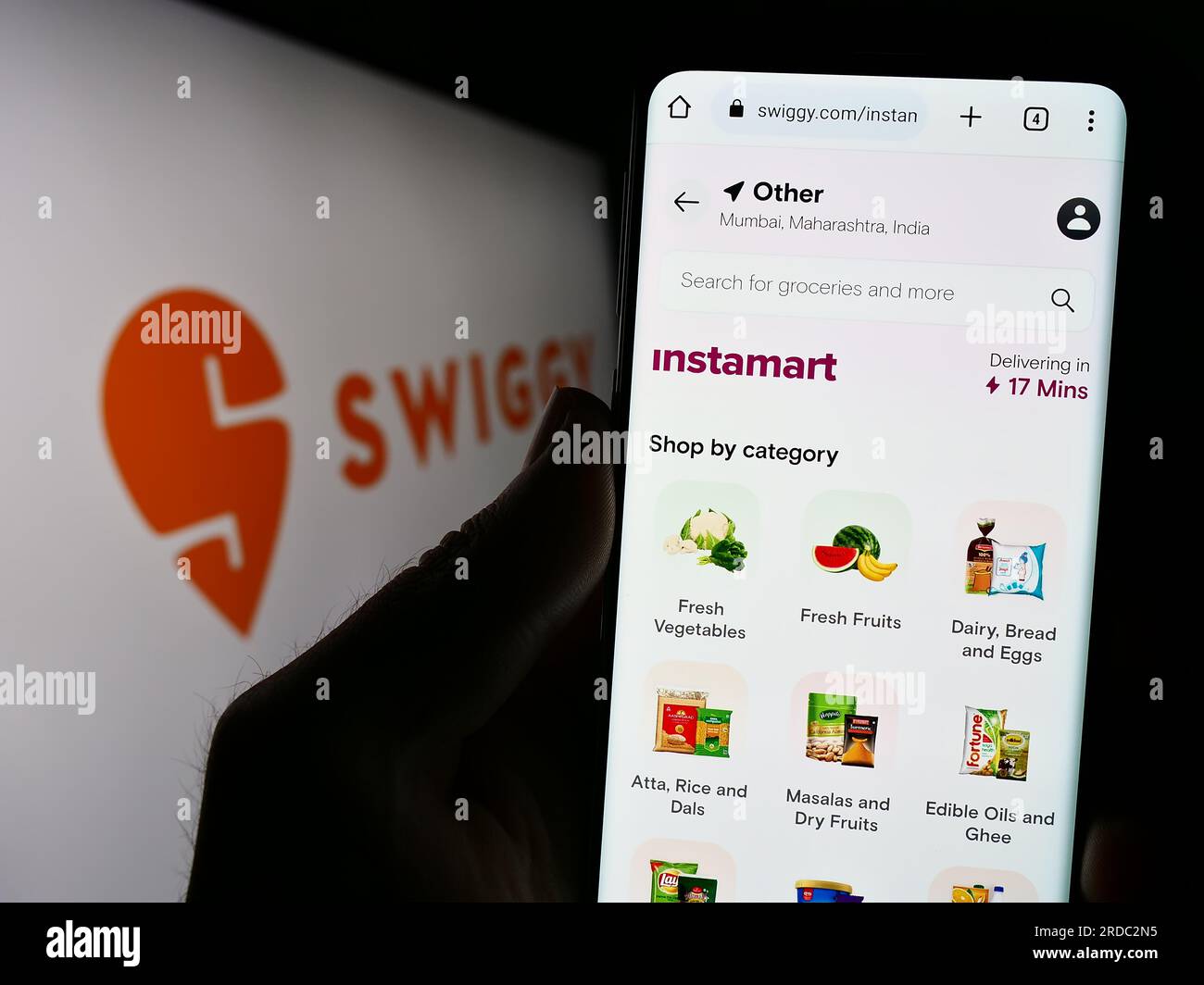 Person holding cellphone with website of Indian food delivery company ...