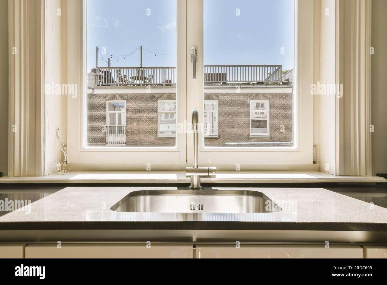 a kitchen sink in front of an open window with the view of a brick wall ...