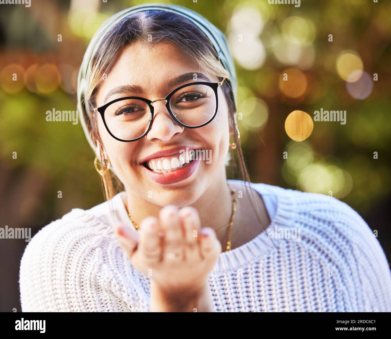 Portrait, smile and blowing a kiss with a woman on a nature green ...