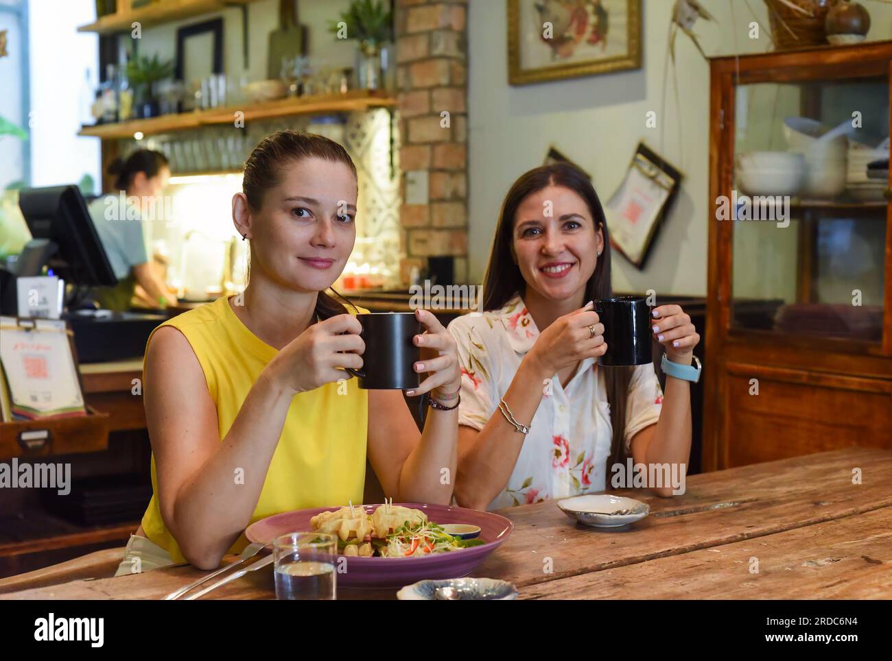 Two best friends talking and eating in a cafe Stock Photo - Alamy