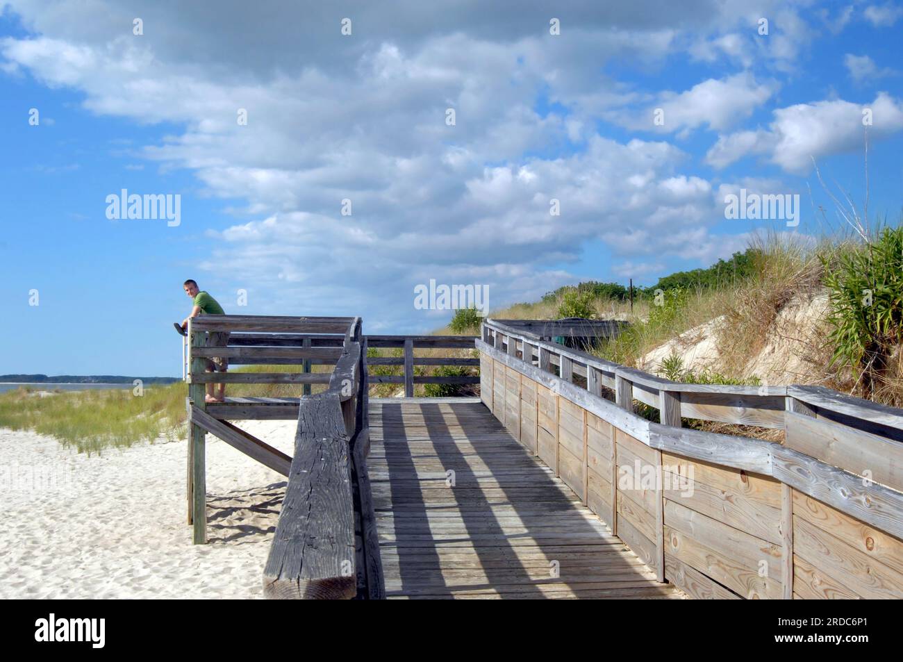 Young man stands barefoot on a weathered dock on the beach at Cape ...
