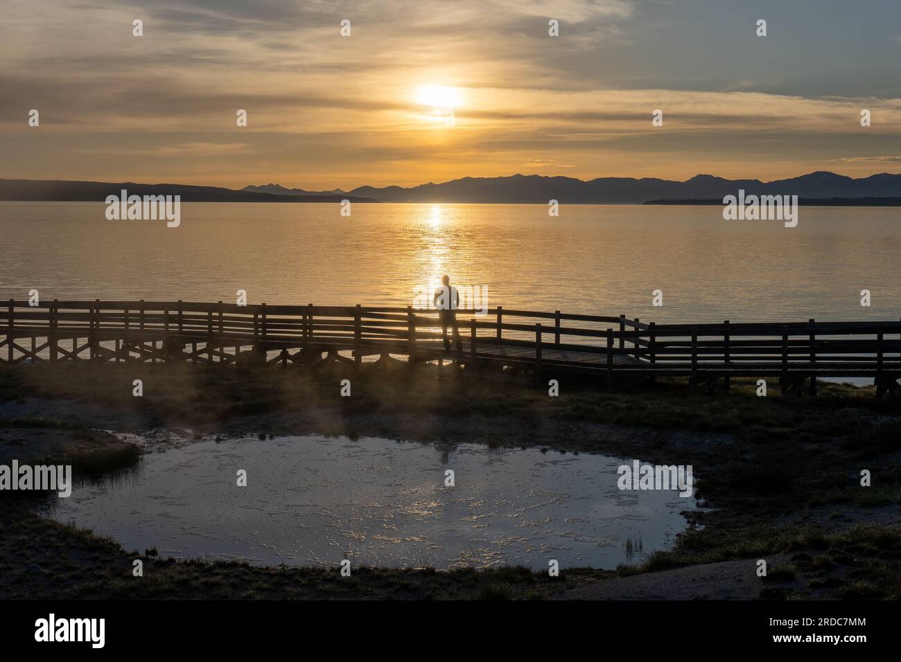 Man standing watching Lakeside Spring while the sun rising behind over ...
