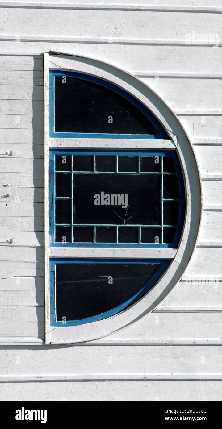 The letter D is formed by a tilted arched window on an old white barn ...