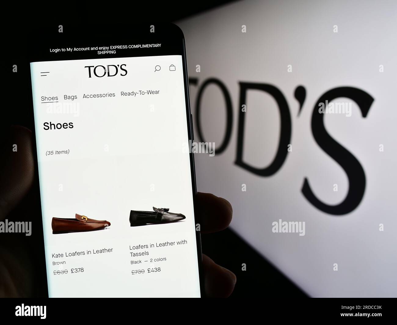 Person holding cellphone with webpage of Italian shoe company Tod's SpA ...