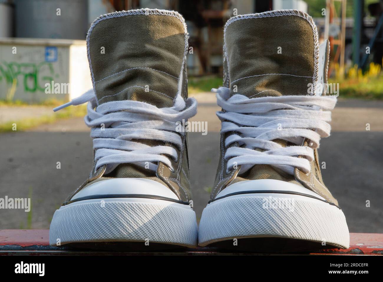 Canvas sneakers with rubber caps stand at the gate of a disused factory ...